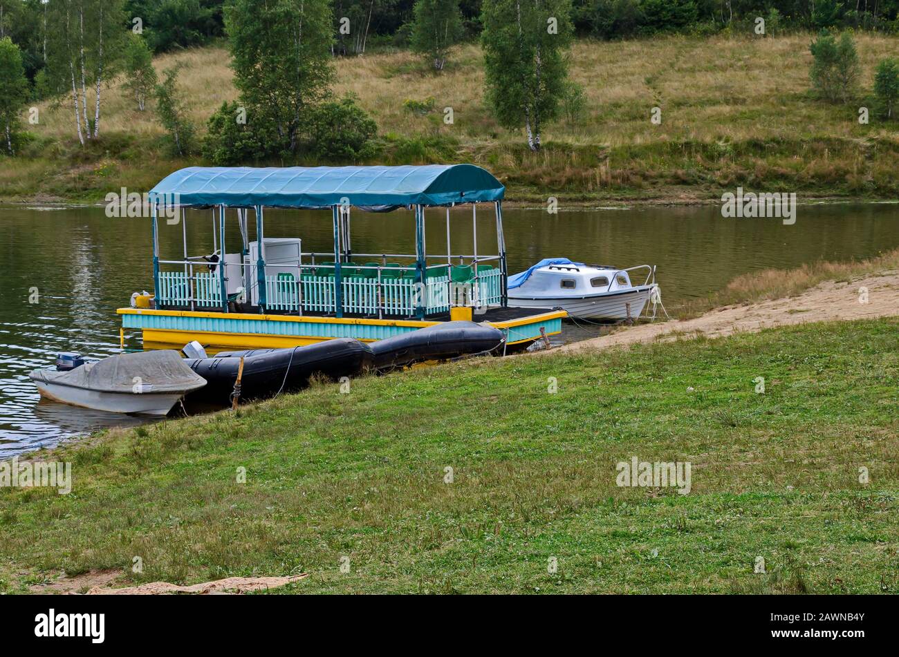 Landscape with mountain, glade, shore and small wharf near artificial ...