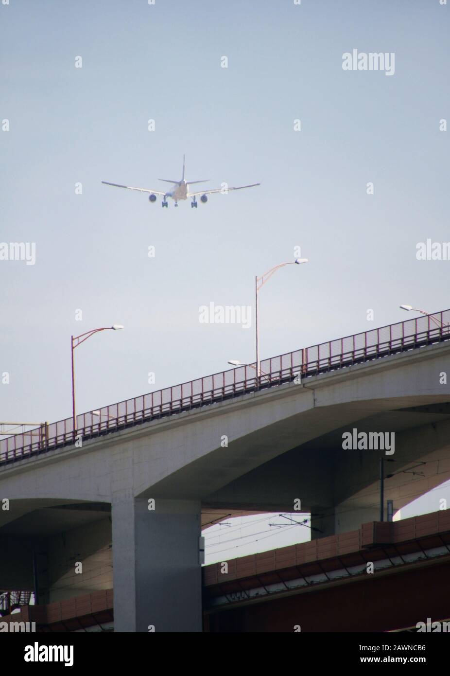 Vertical shot of an airplane flying over a bridge Stock Photo - Alamy