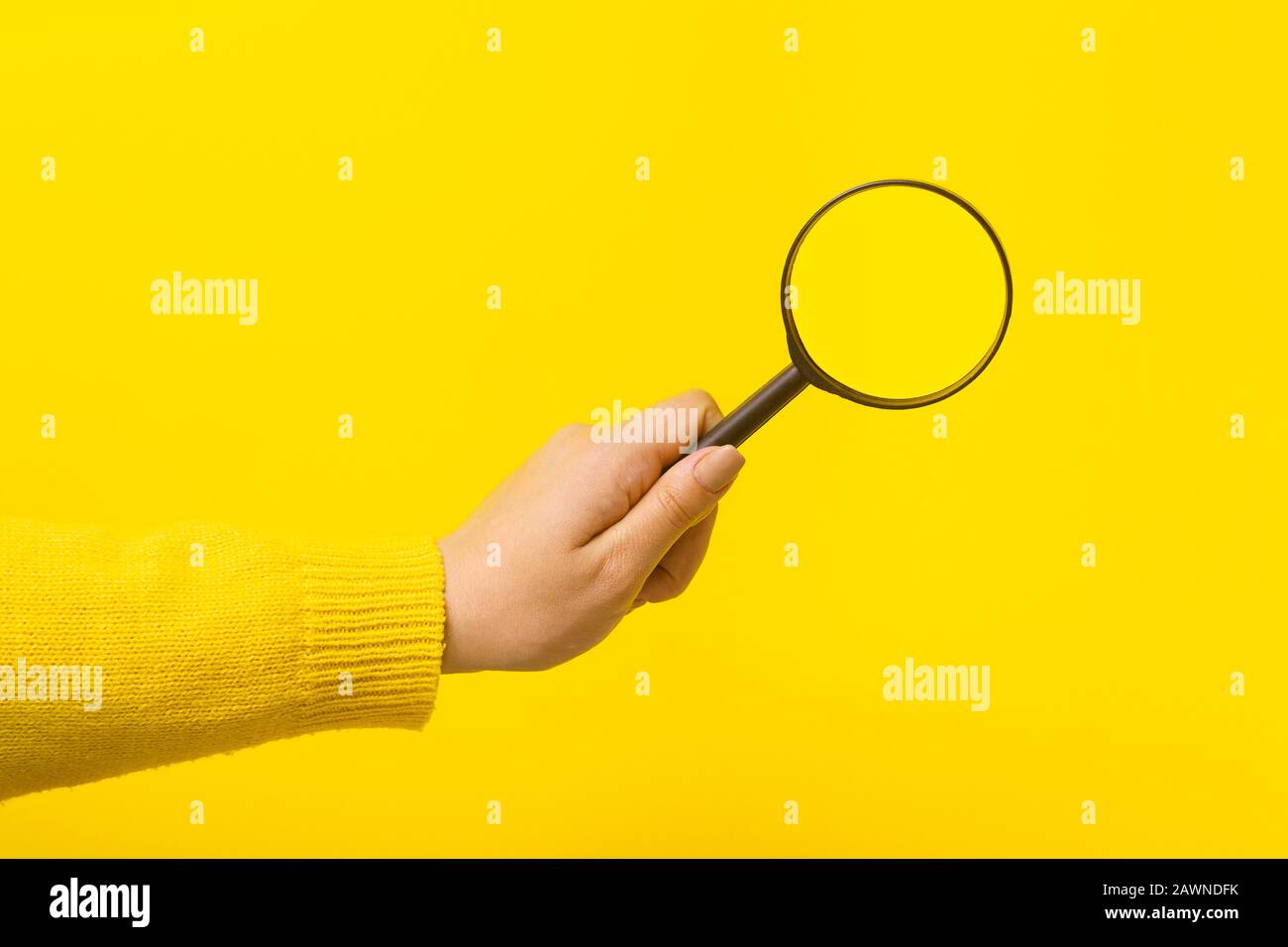 magnifier in hand over yellow background Stock Photo - Alamy