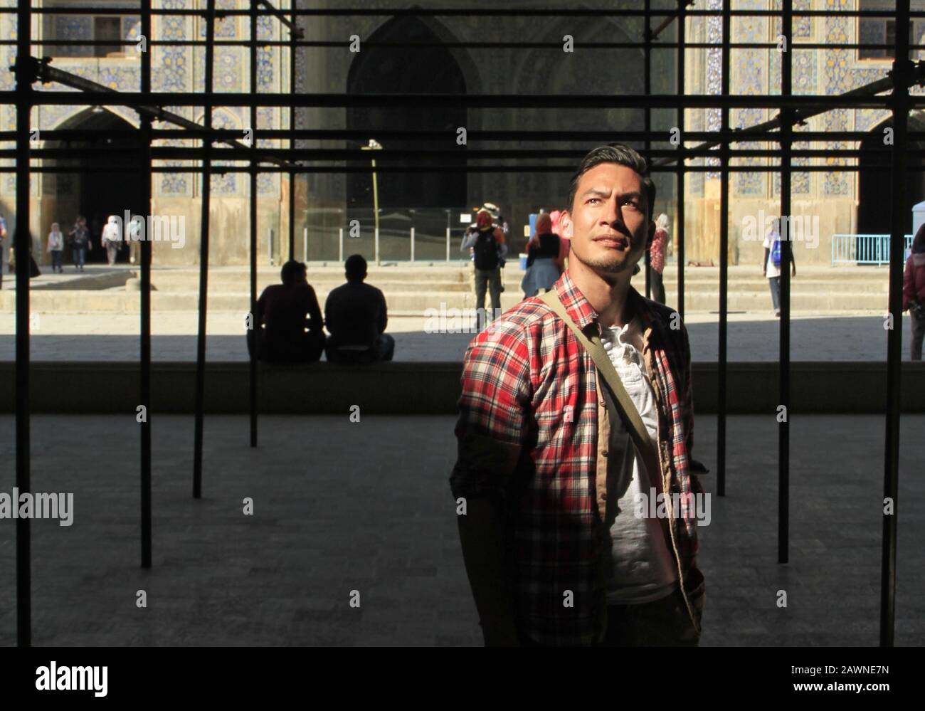 Man standing behind a metal construction and a building surrounded by ...