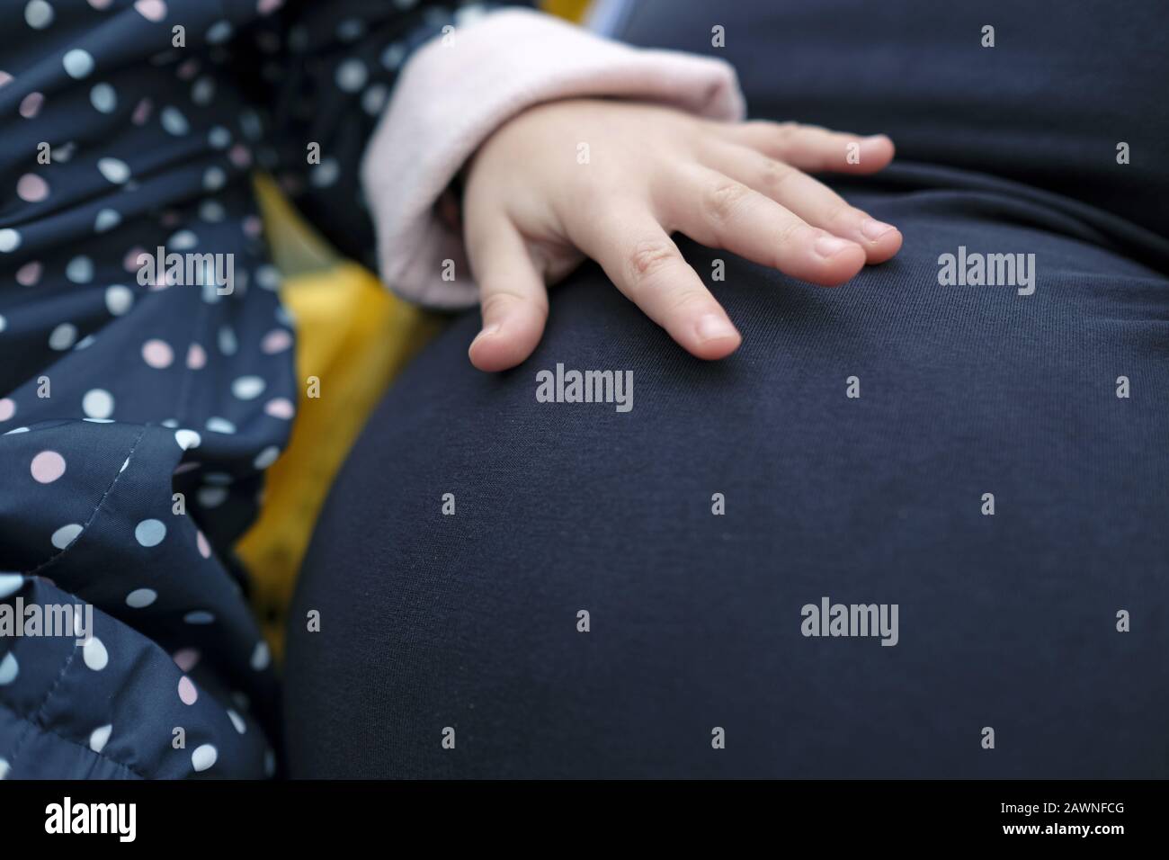 Closeup shot of a child putting his hand on the belly of the pregnant ...
