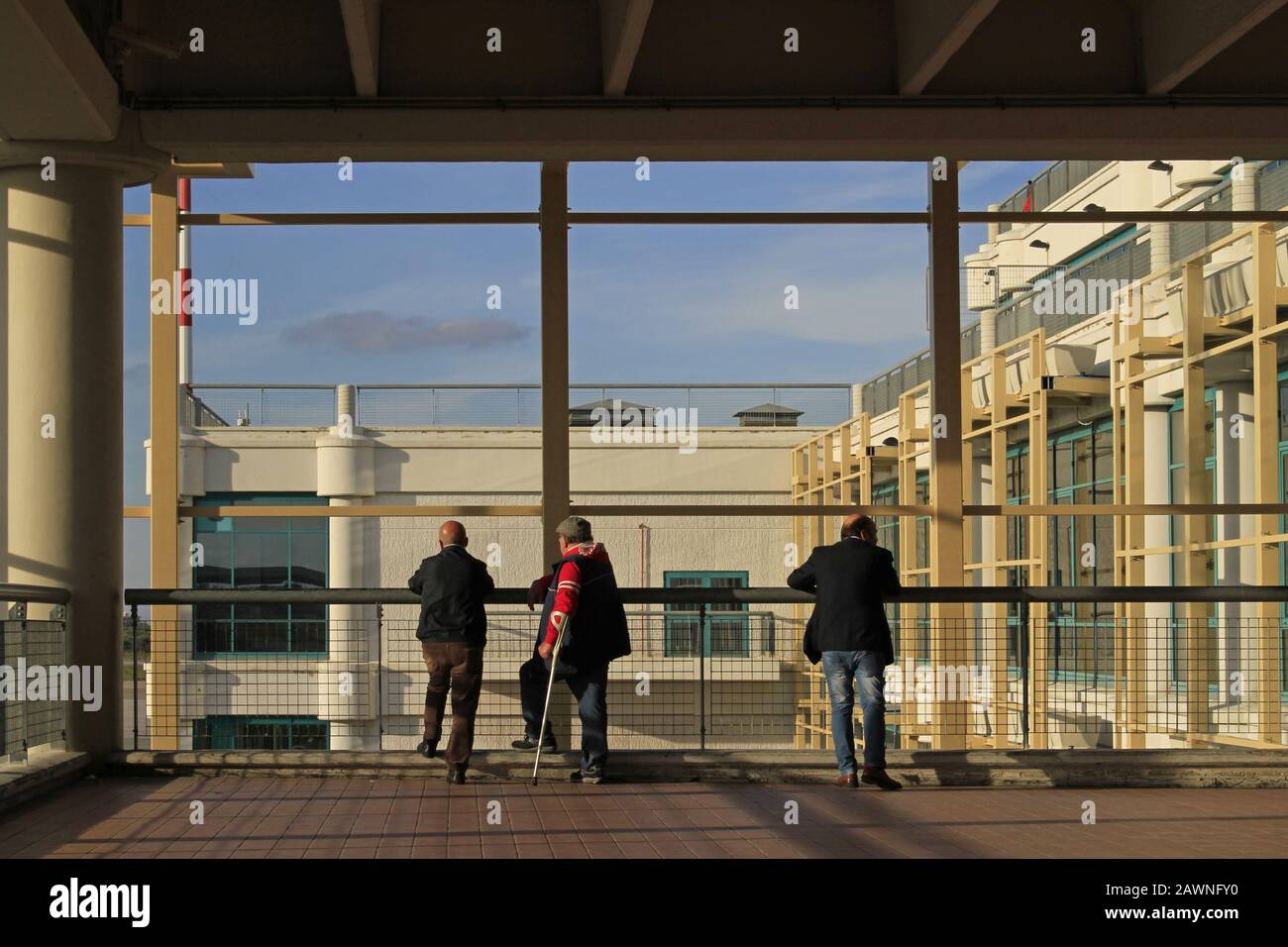 Men standing and looking down from the building Stock Photo - Alamy