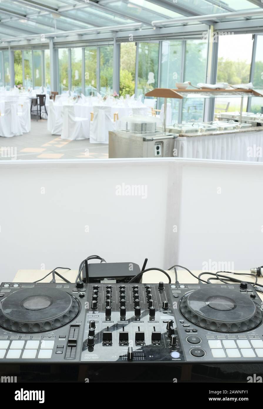 Vertical shot of a DJ deck in a beautiful white wedding venue before ...