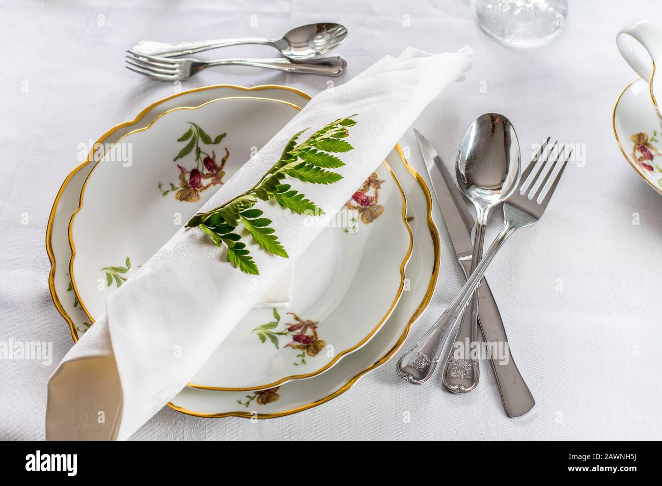Luxury table setting with crystal glasses, porcelain dishes and floral ...