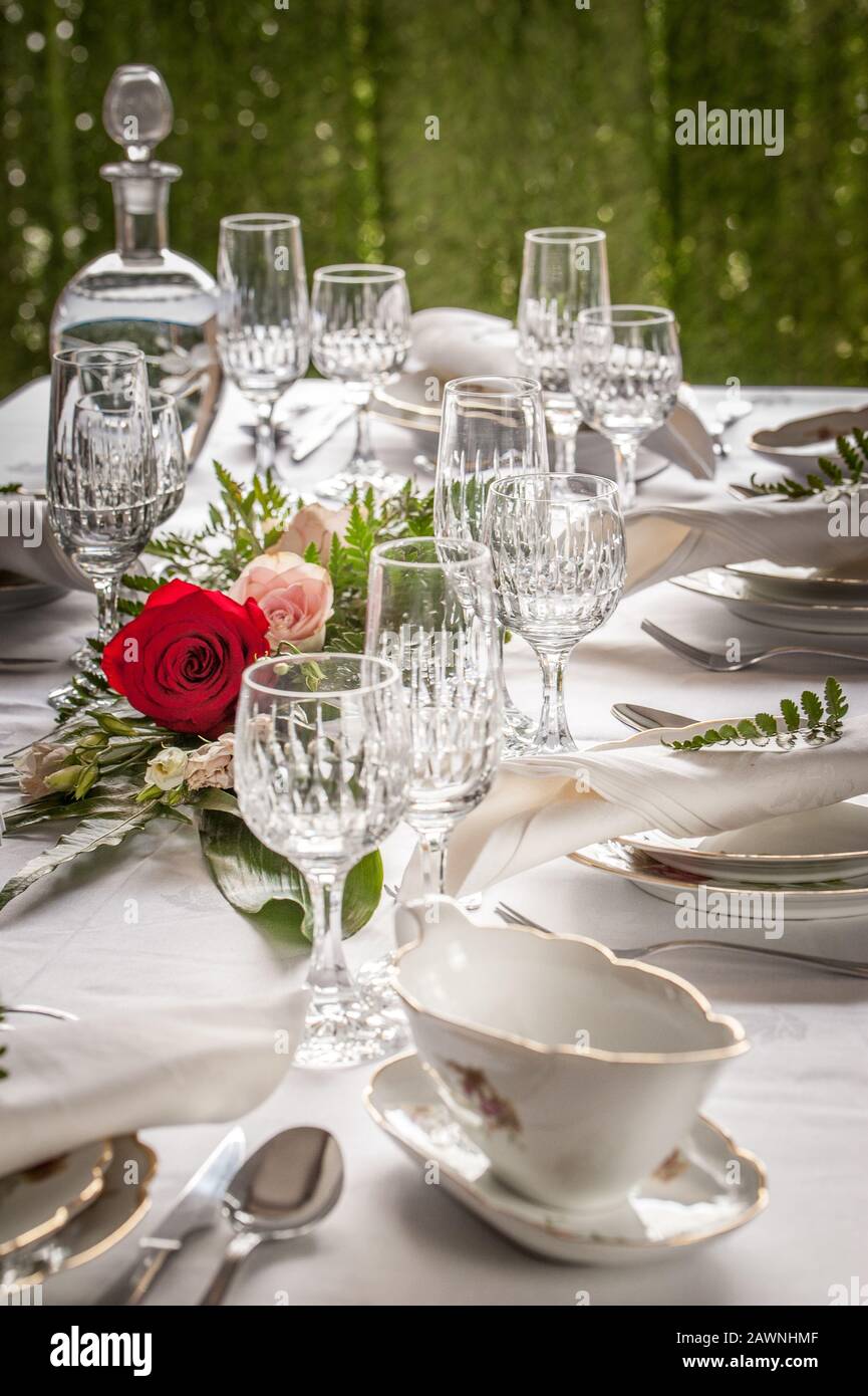 Luxury table setting with crystal glasses, porcelain dishes and floral ...