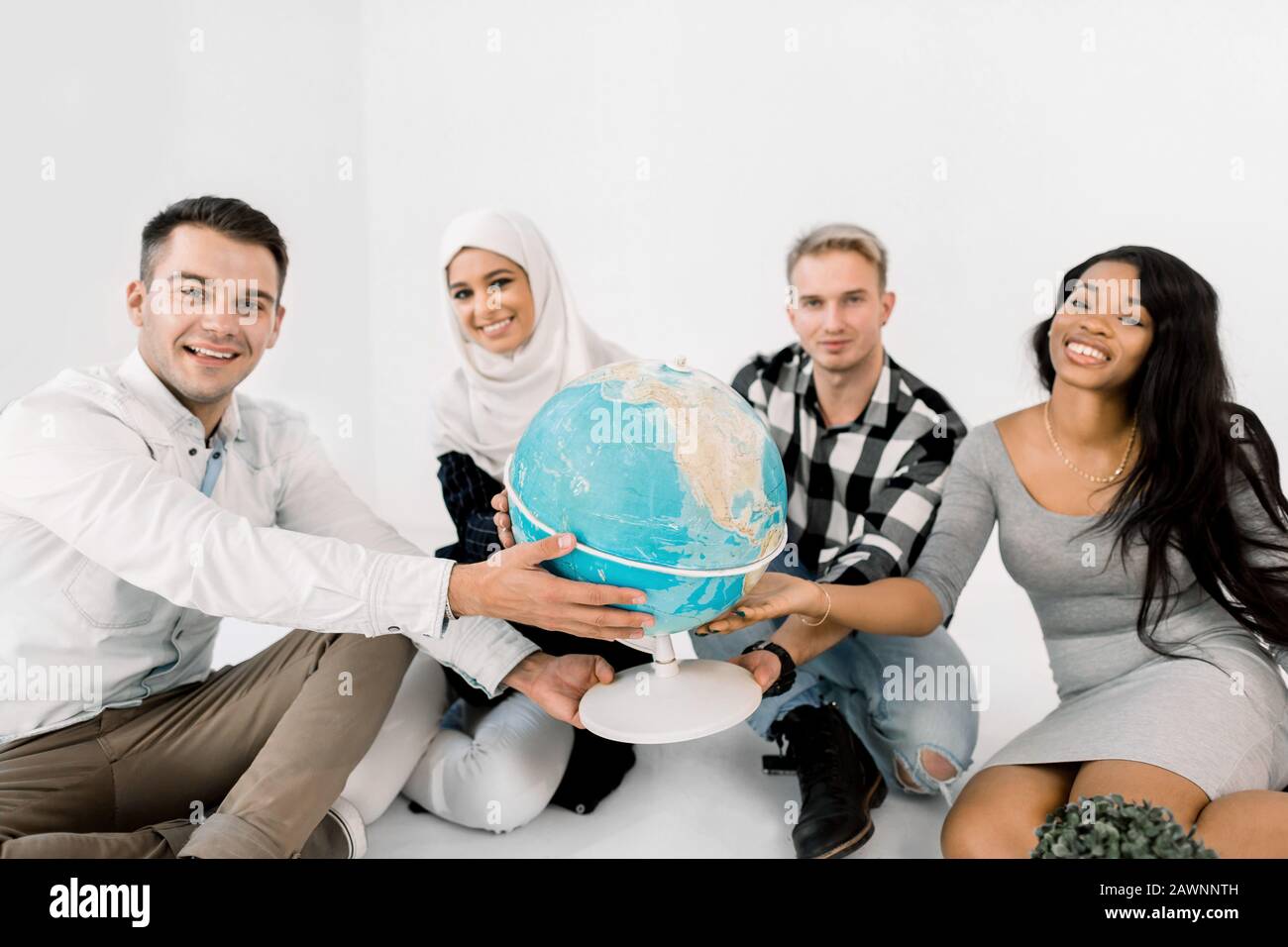 Four young multiracial people holding hands and hug Earth globe ...