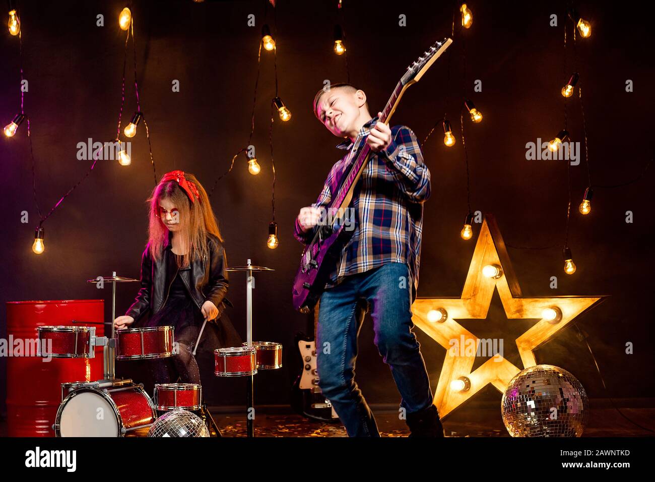 Kids pretending to be in a rock band and play and sing at studio or ...