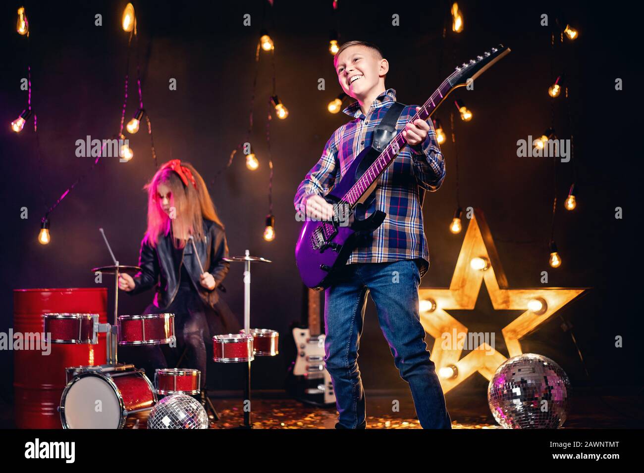 Kids pretending to be in a rock band and play and sing at studio or ...