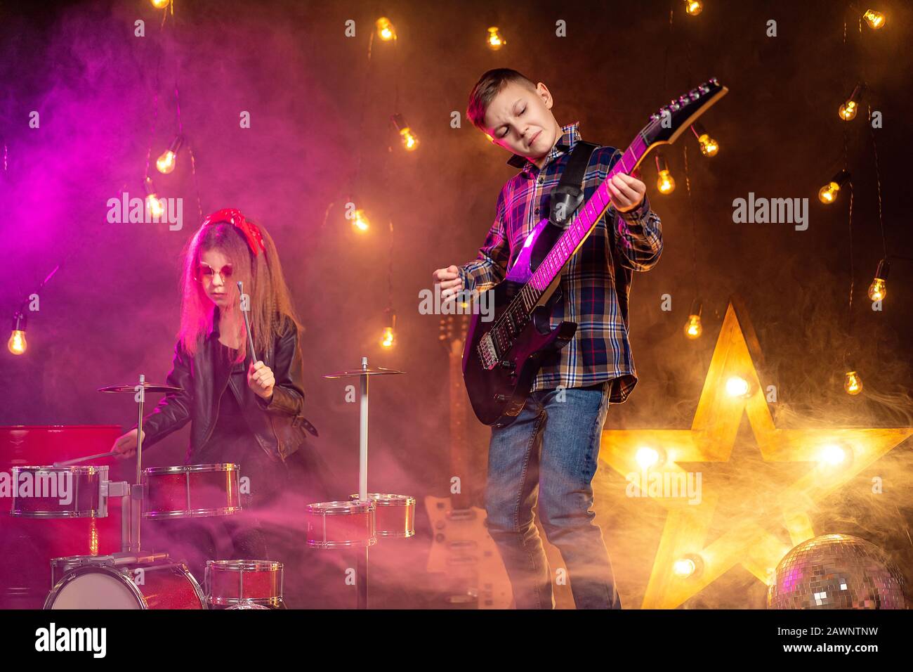 Kids pretending to be in a rock band and play and sing at studio or ...