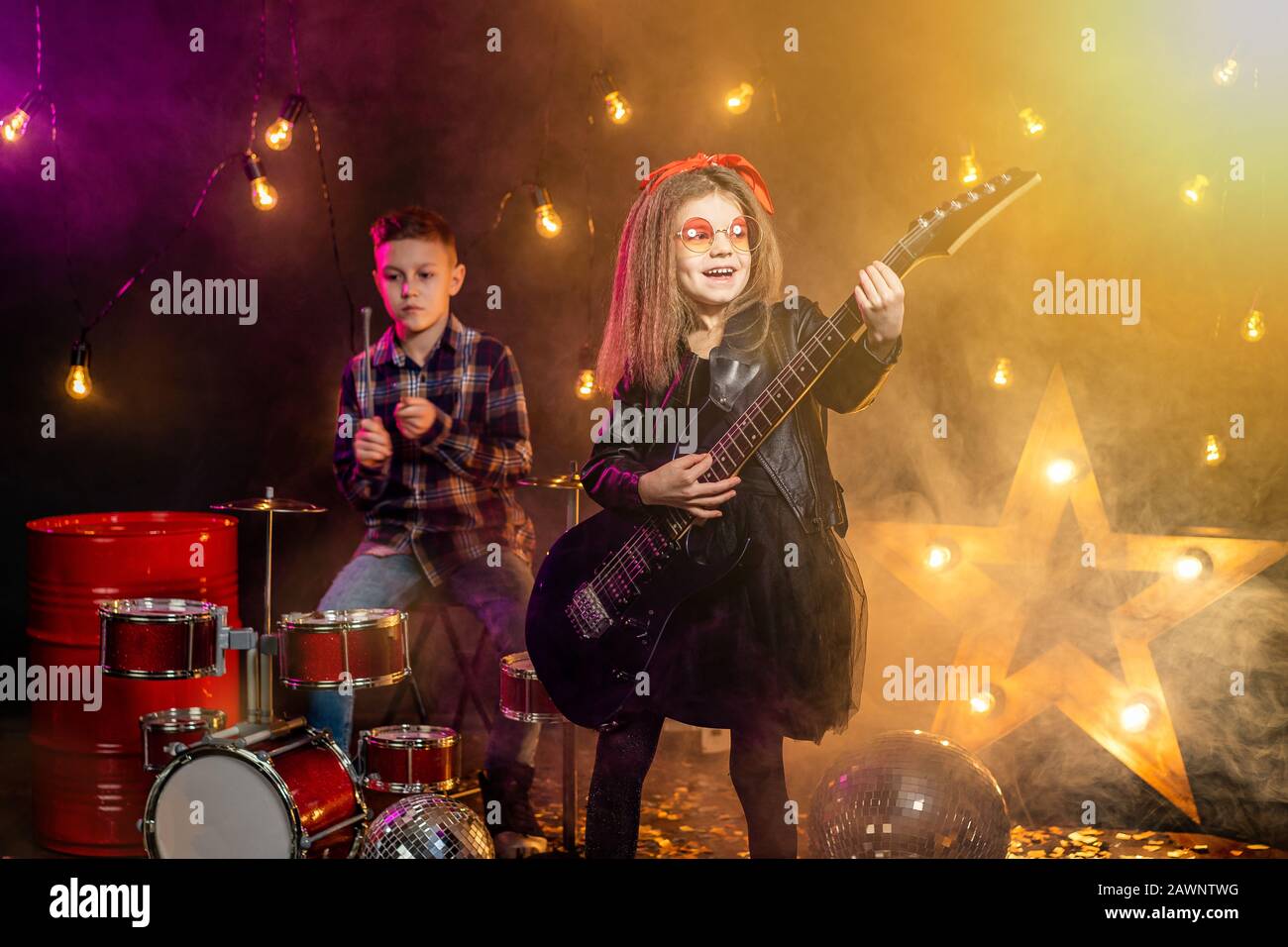 Kids pretending to be in a rock band and play and sing at studio or ...