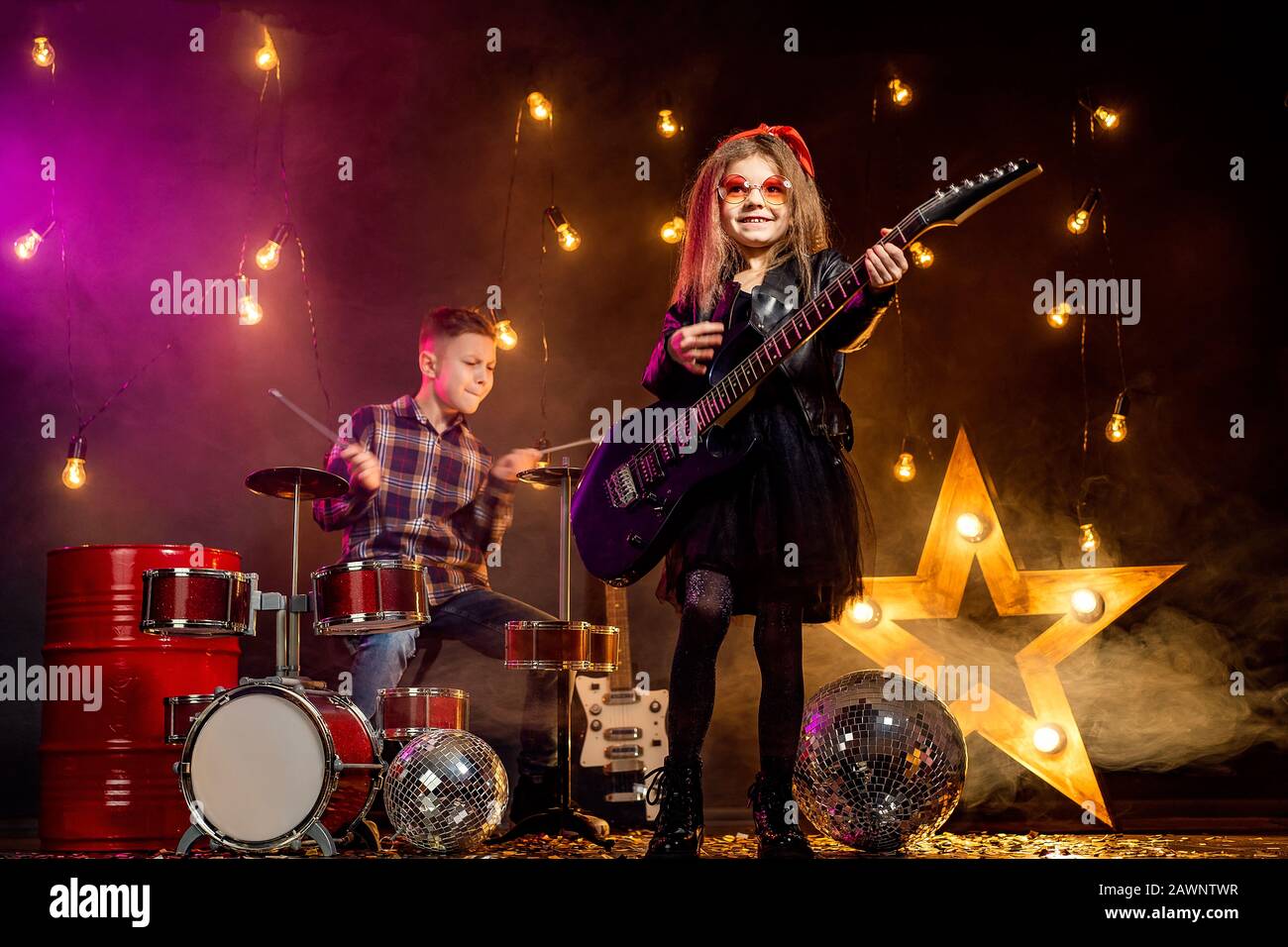 Kids pretending to be in a rock band and play and sing at studio or ...