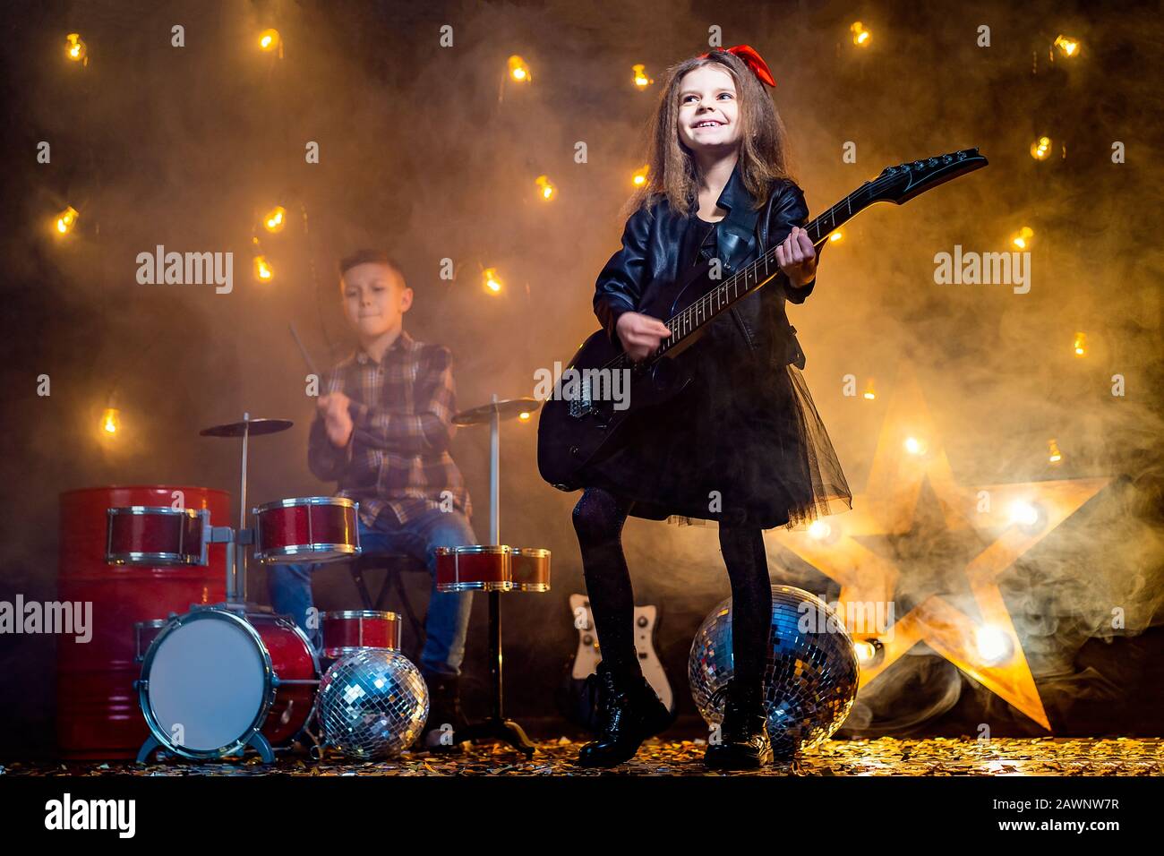 Kids pretending to be in a rock band and play and sing at studio or ...