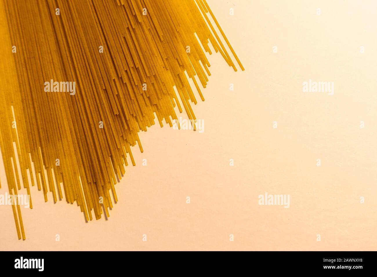Thin, long, uncooked and dry spaghettini noodles are spread out on a ...