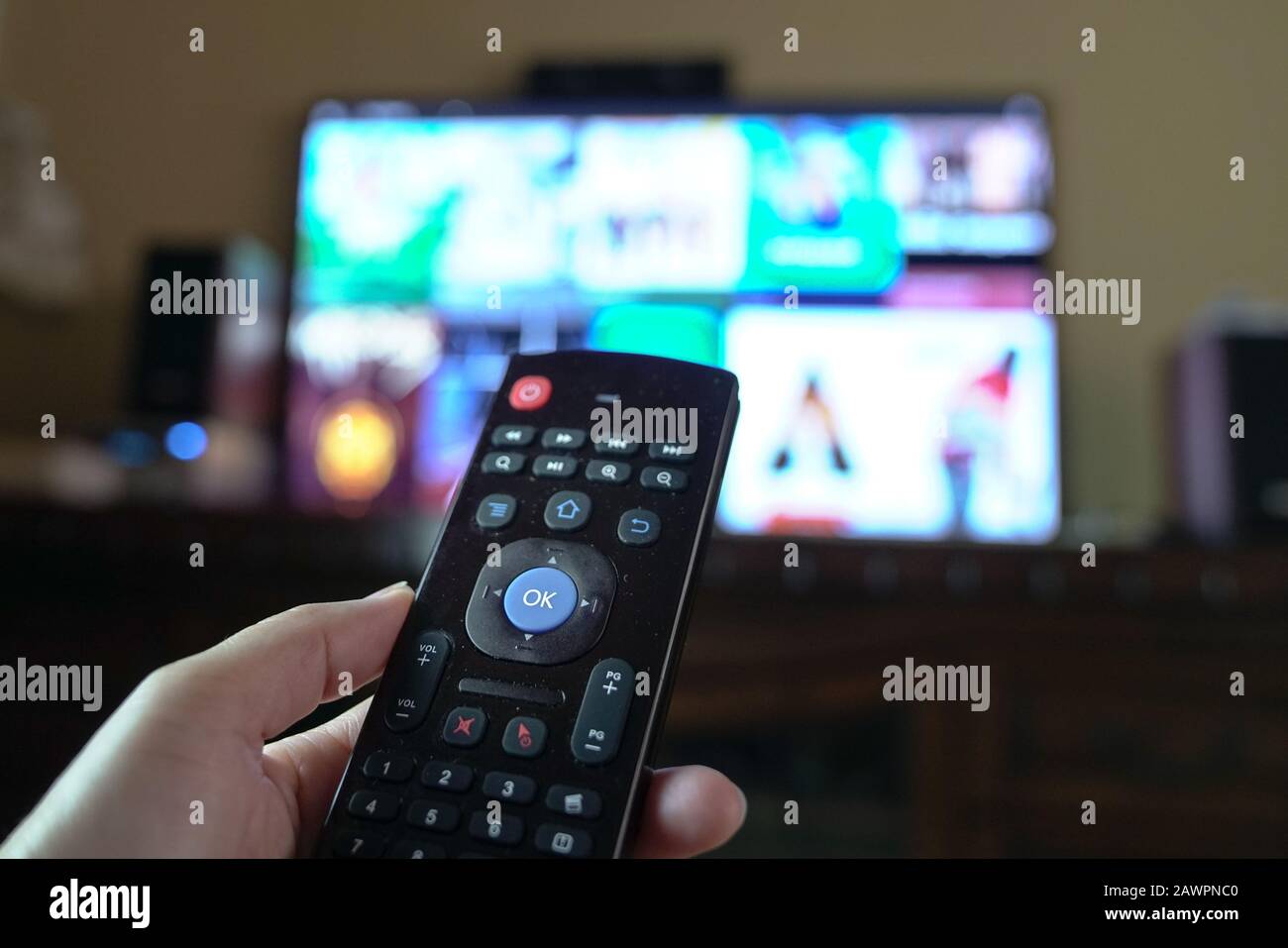 Female hand holding a smart tv remote control, pointing towards tv ...