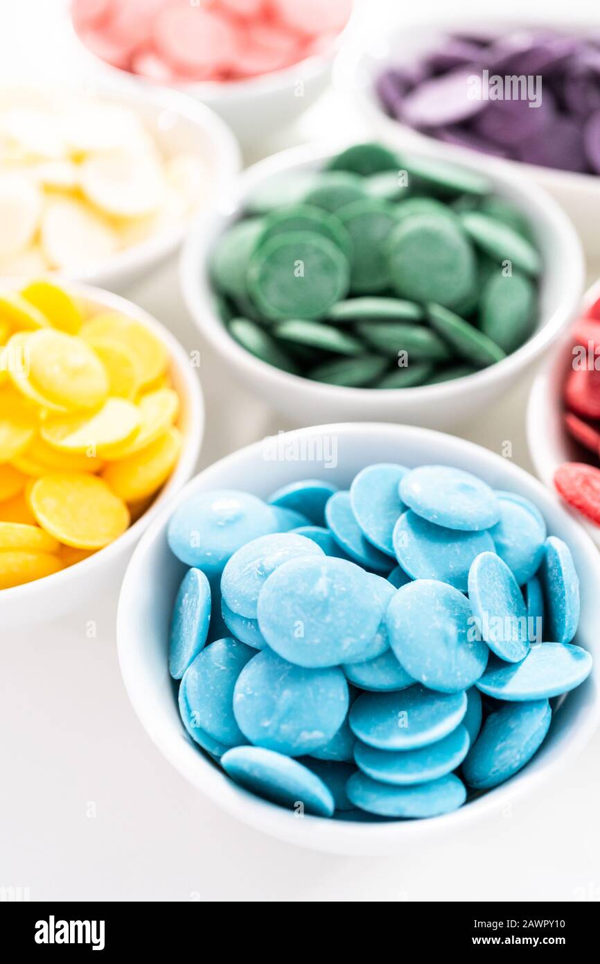 Rainbow colors of round chocolate chips in a white bowls for melting ...