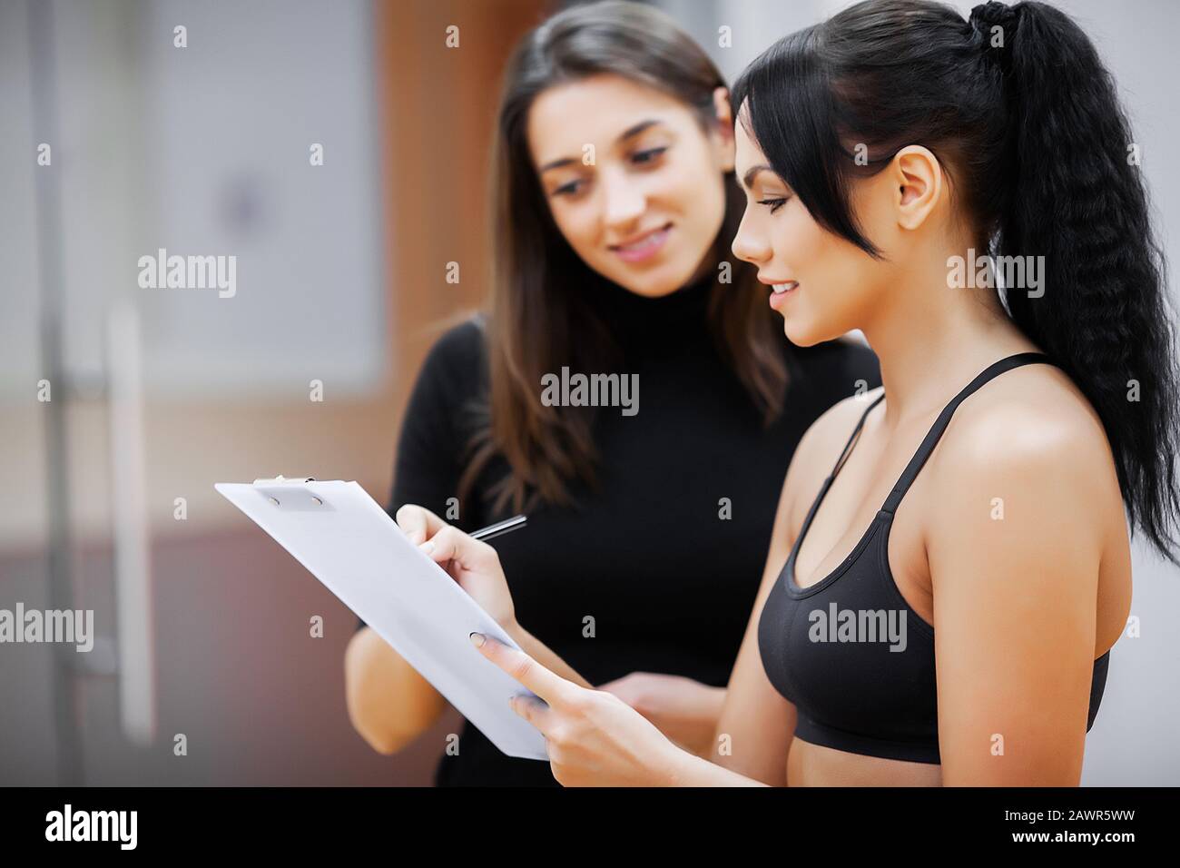 Female trainer teaching woman doing exercise in gym Stock Photo - Alamy