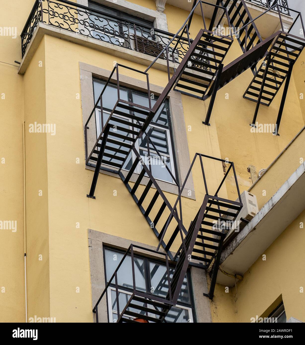 Low angle shot of a series of fire escape staircase outside a yellow ...