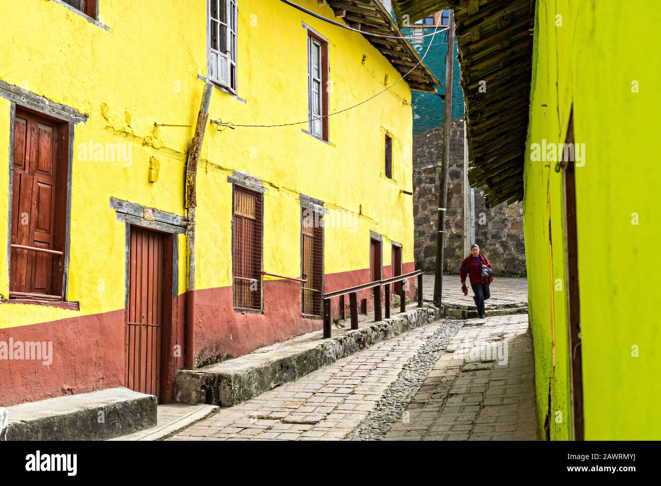 A bright yellow building and cobblestone alley in Angangueo, Michoacan ...