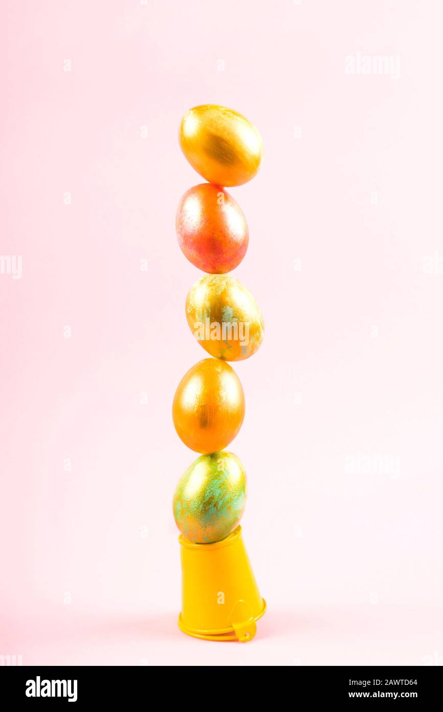 Painted Easter eggs are arranged in a vertical tower and balance on a ...