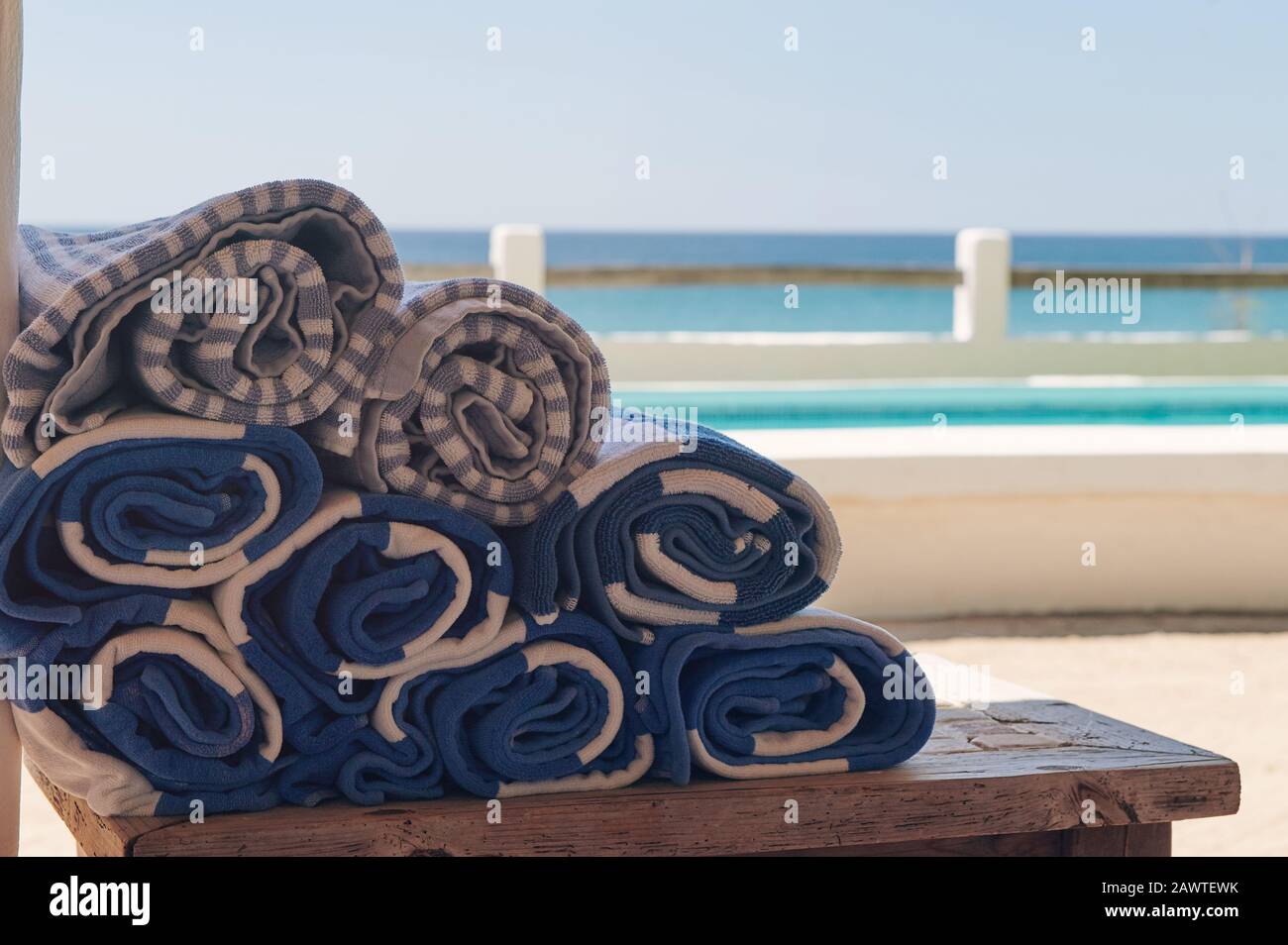 Pile of pool towels on wooden table in beach background Stock Photo - Alamy