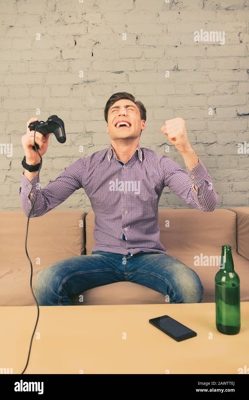 Excited man winning video game and triumphing with raised hands Stock ...