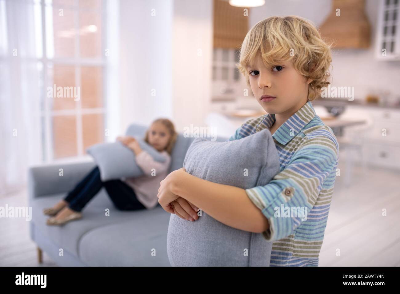 Blond cute boy with a pillow in his hands feeling sad Stock Photo - Alamy