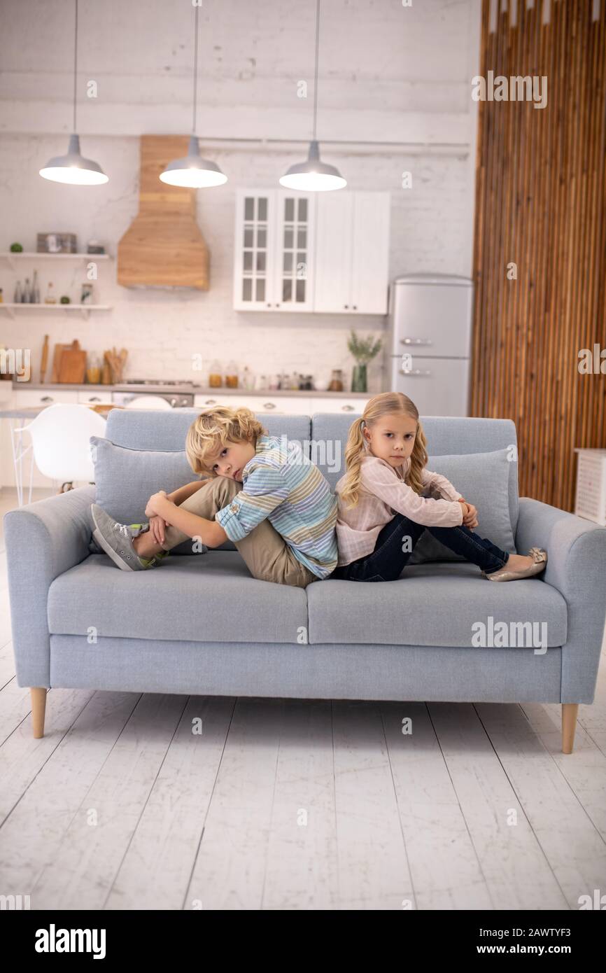Kids sitting back to back and hugging knees Stock Photo - Alamy