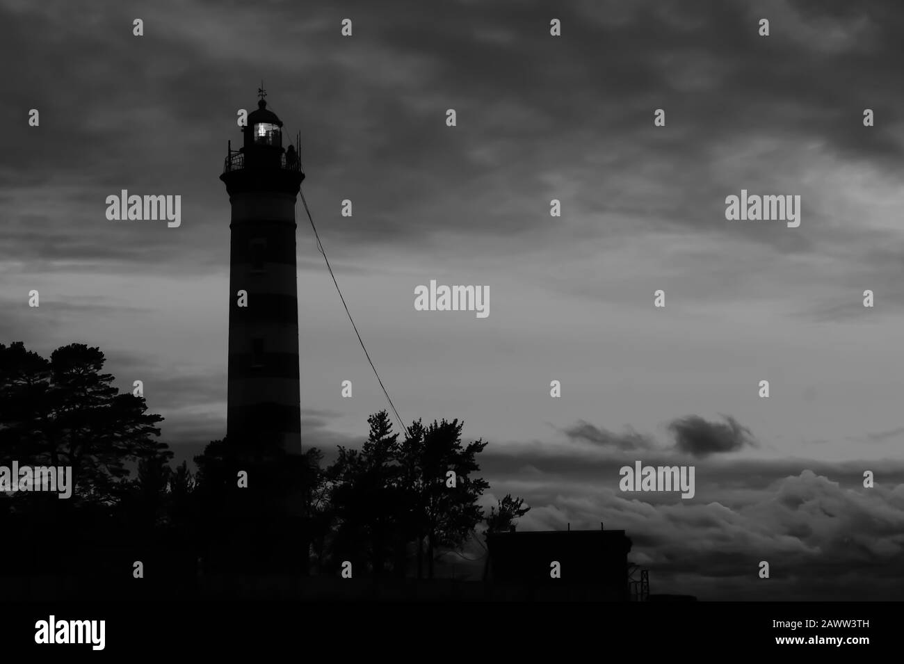 Lighthouse tower shines in the dark with a dramatic sky. silhouette of ...