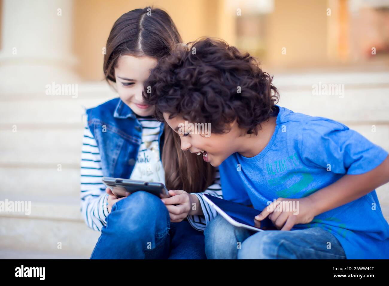 Two kids boy and girl playing games on tablet outdoor. Children and ...