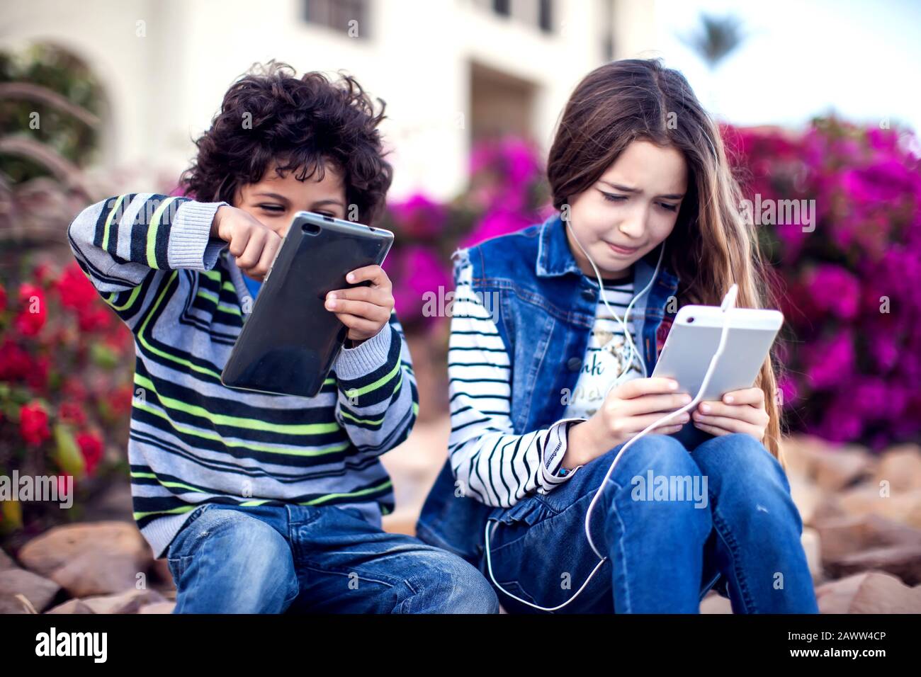 Two kids boy and girl playing games on tablet outdoor. Children and ...