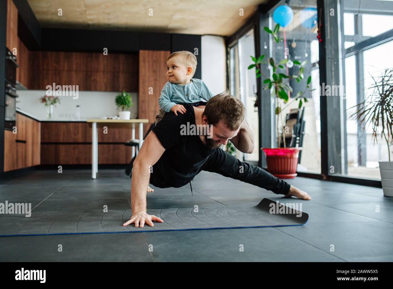 baby sitting on the back of the father doing single arm plank Stock ...