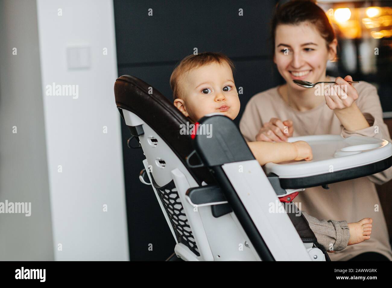 Child sitting on a high chair, getting breakfast from his mother Stock ...