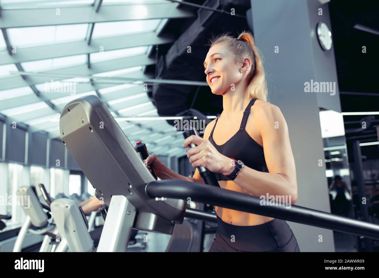 Young muscular caucasian woman practicing in gym, doing cardio ...
