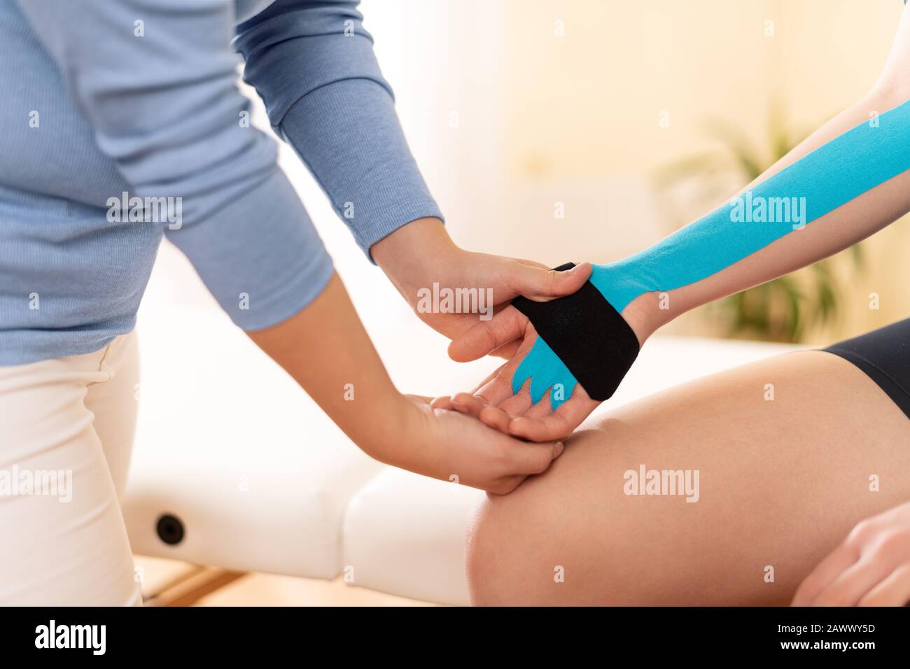 Female physiotherapist applying kinesio tape on patient's arm. Kinesiology, physical therapy ...