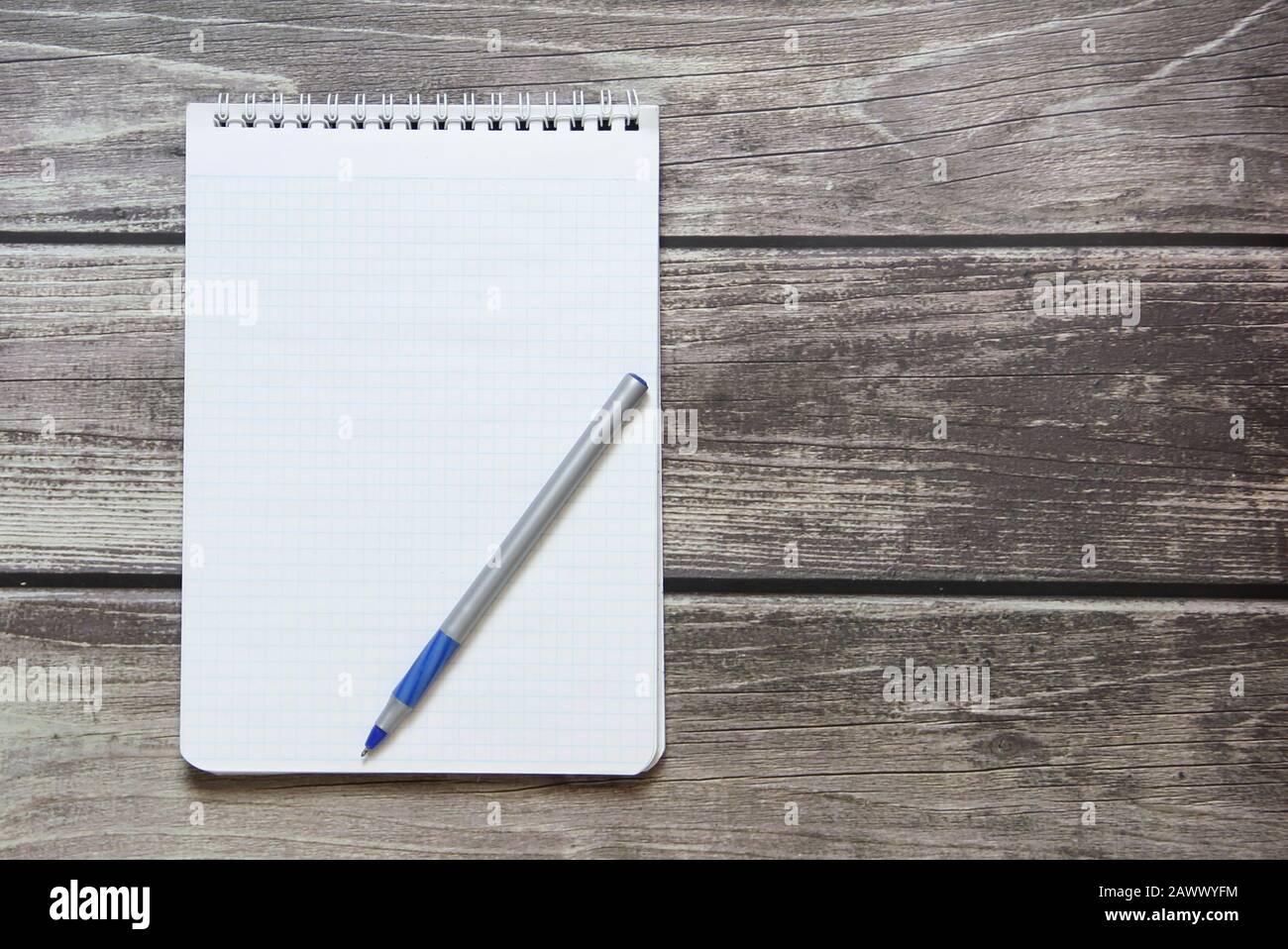 Notepad with a blank white sheet in a checker paper with ball pen lies ...