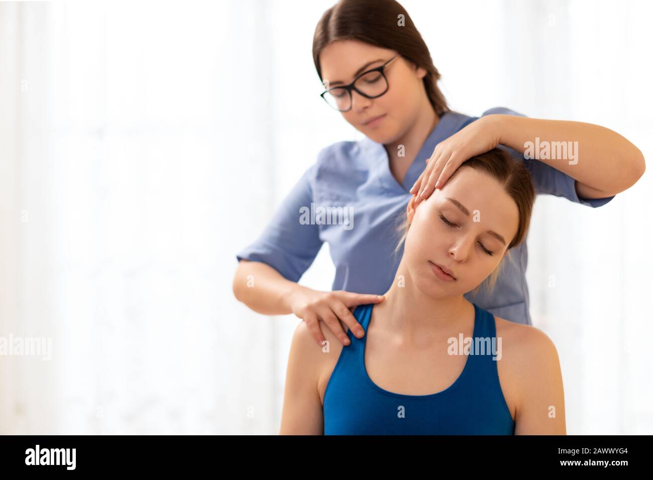 Female physiotherapist or a chiropractor adjusting patients neck ...