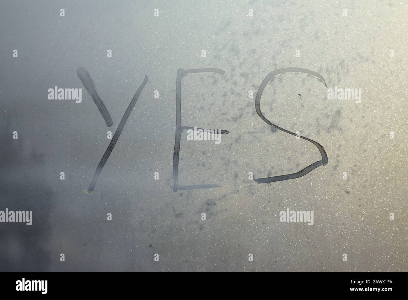 The inscription on frozen window pane. Word yes written on blurry ...