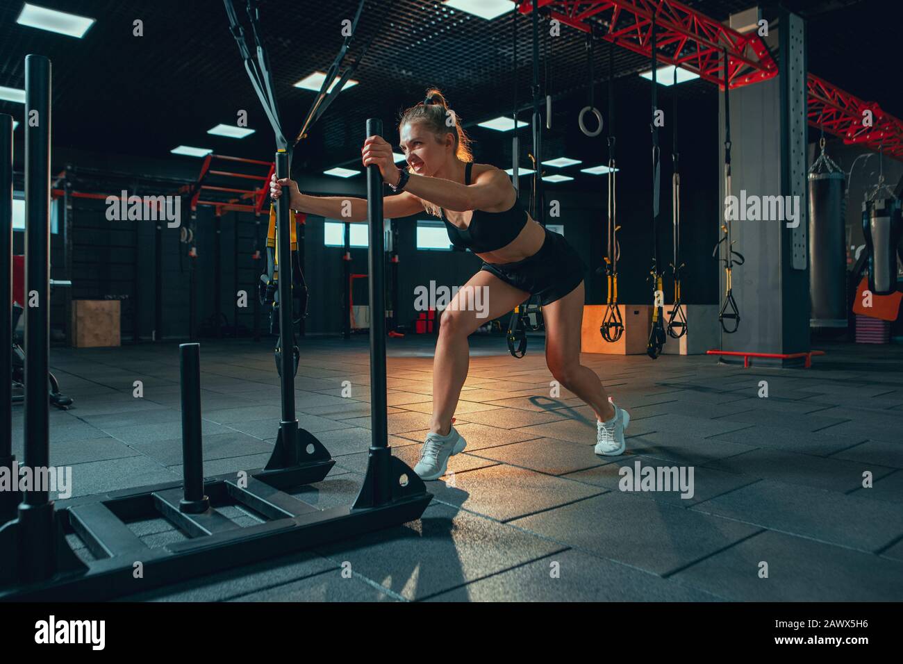 Energy. Young muscular caucasian woman practicing in gym with the ...