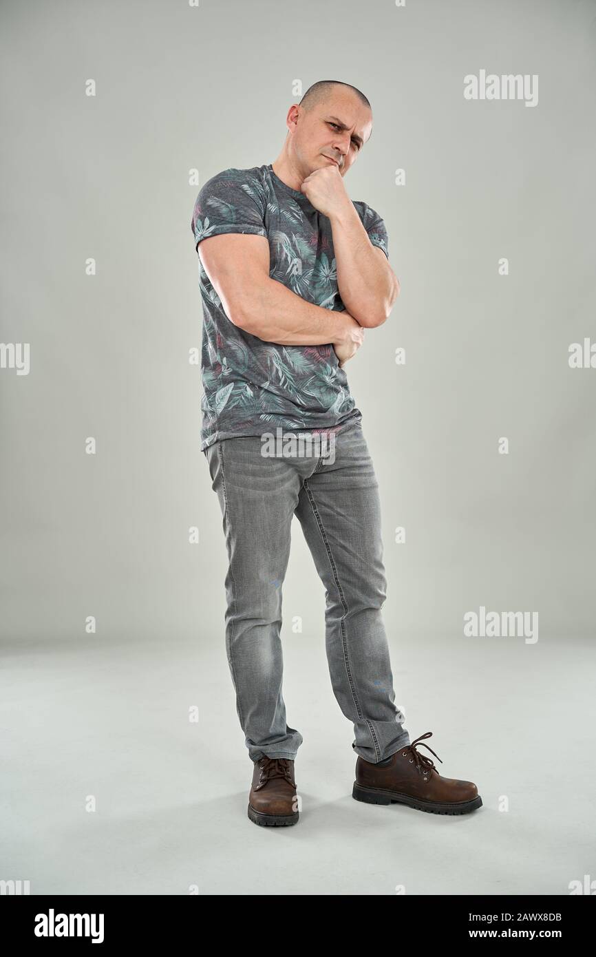 Suspicious man looking sideways at the camera, full length studio shot ...
