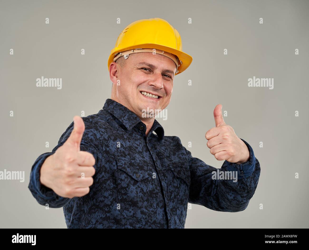 Engineer in hard hat making thumbs up sign Stock Photo - Alamy