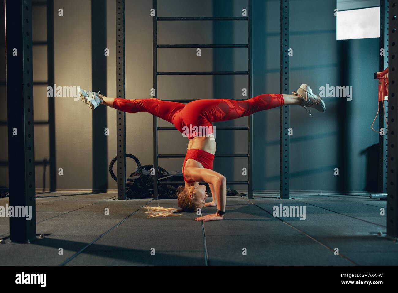 Balanced. Young muscular caucasian woman practicing in gym. Athletic ...