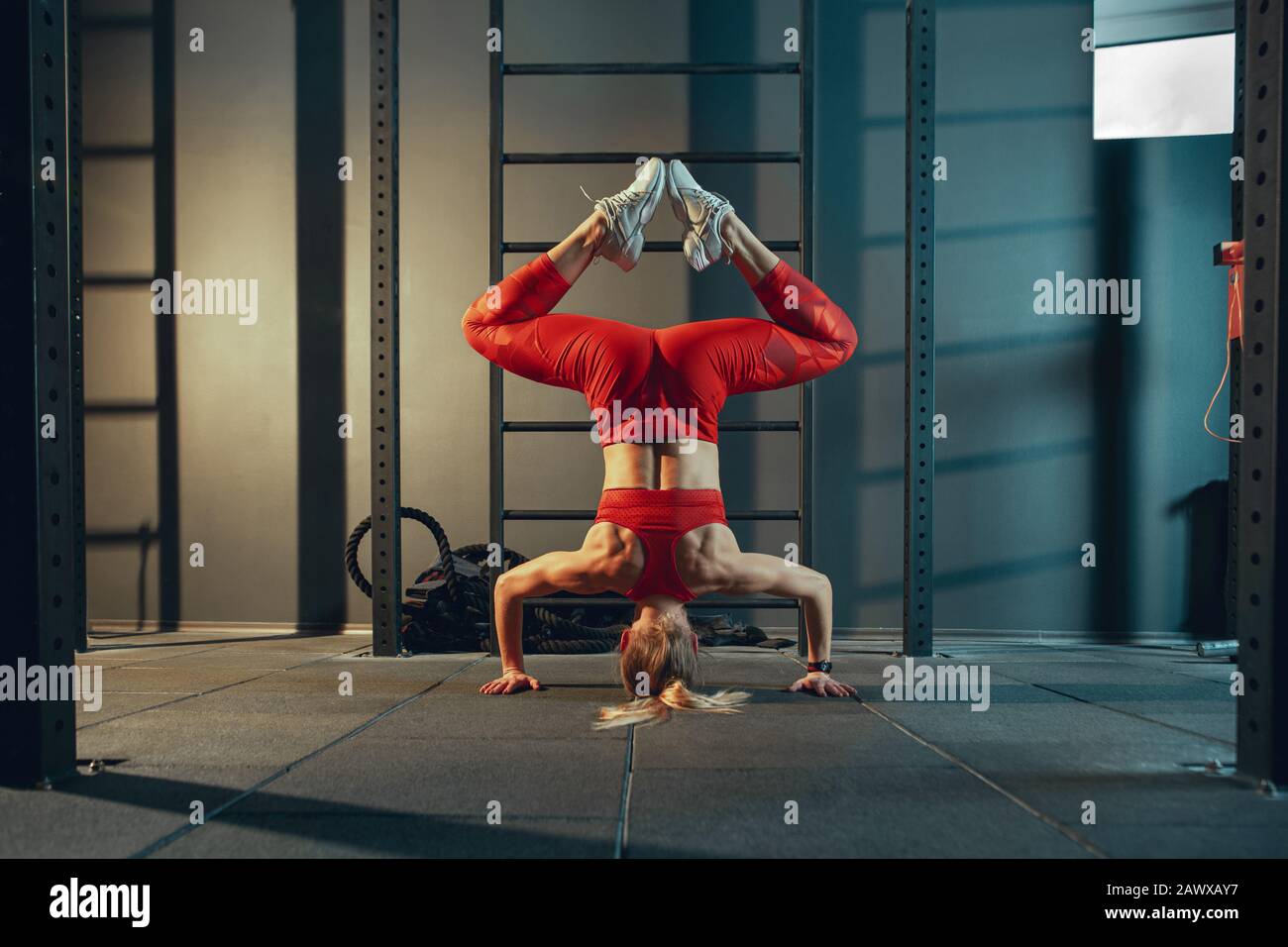 Balanced. Young muscular caucasian woman practicing in gym. Athletic ...