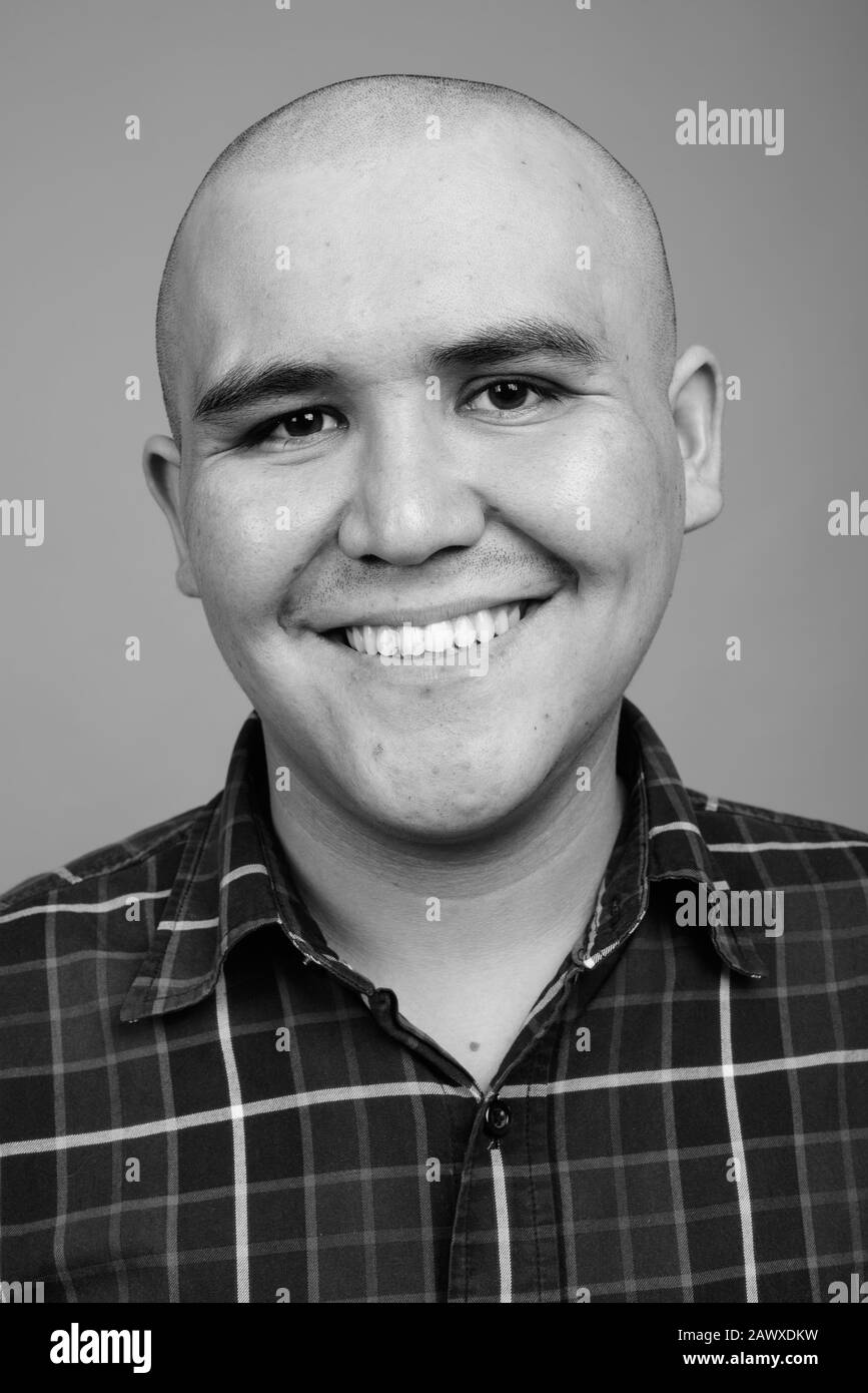 Young bald Asian businessman against gray background Stock Photo - Alamy
