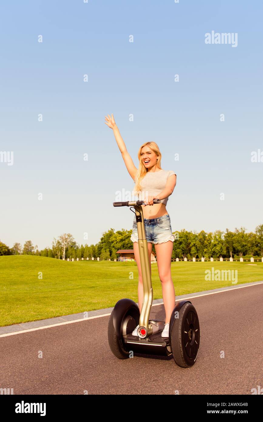 Pretty happy girl with raised hand riding a segway Stock Photo - Alamy
