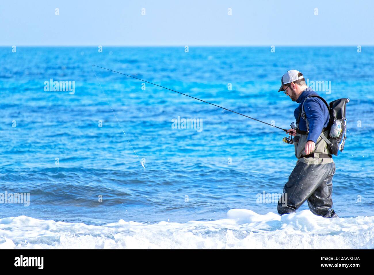 Fisherman standing at the seashore cast the fishimg rod. Sportsman ...