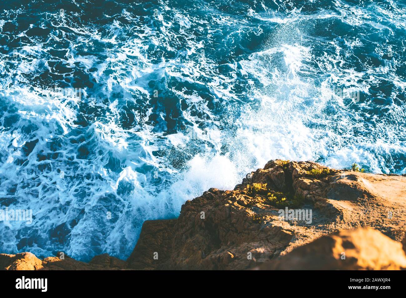 top view of sea waves hitting rocks on the beach with turquoise blue ...