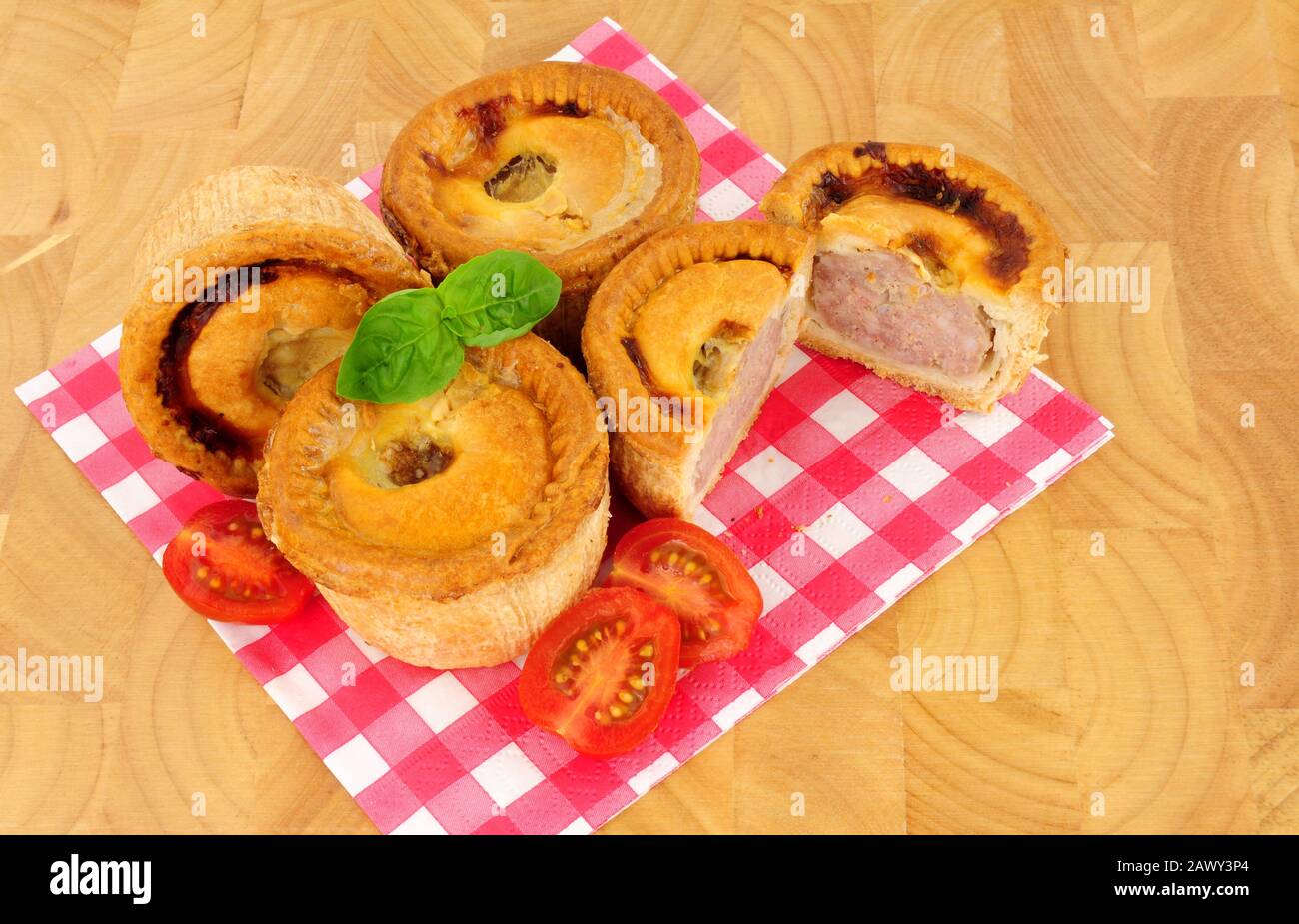 Group of savoury crusty pork pies on a paper gingham pattern napkin ...