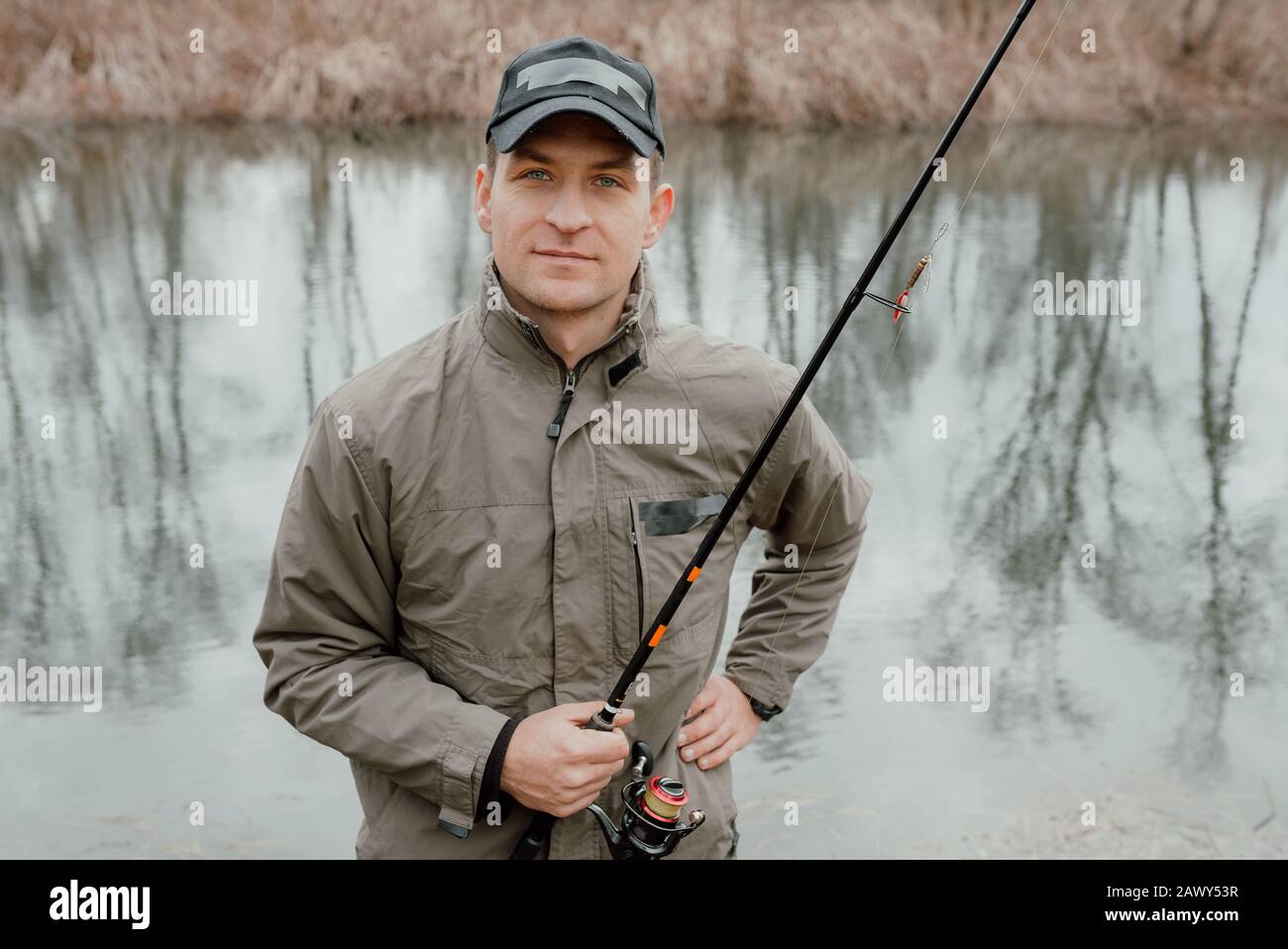 Young man standing with fishing rod Stock Photo - Alamy