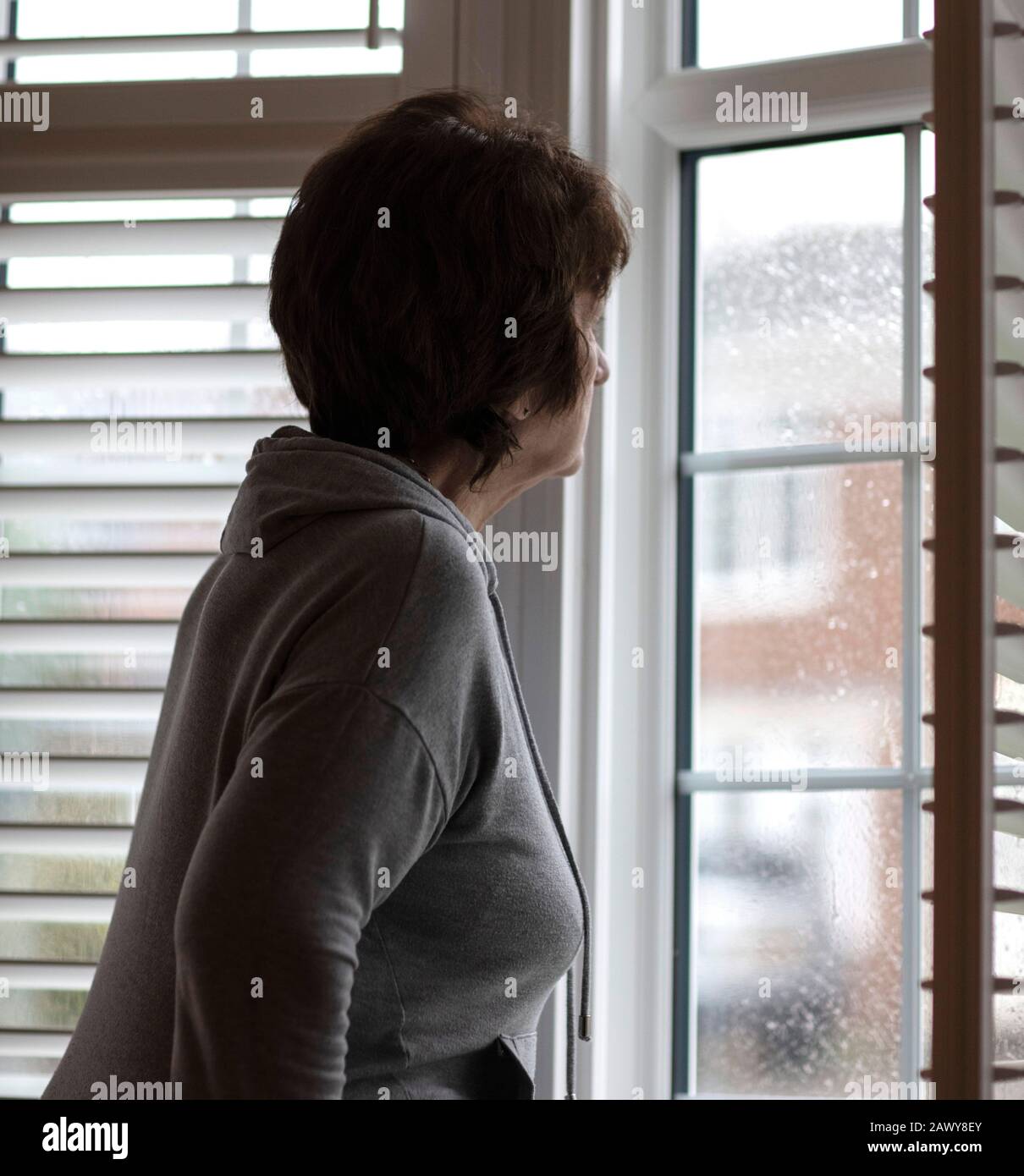 A lady at home, watching rain hit her window Stock Photo - Alamy