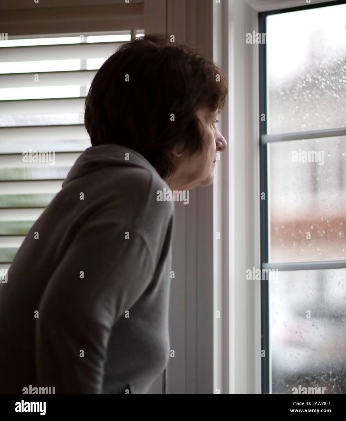 A lady at home, watching rain hit her window Stock Photo - Alamy